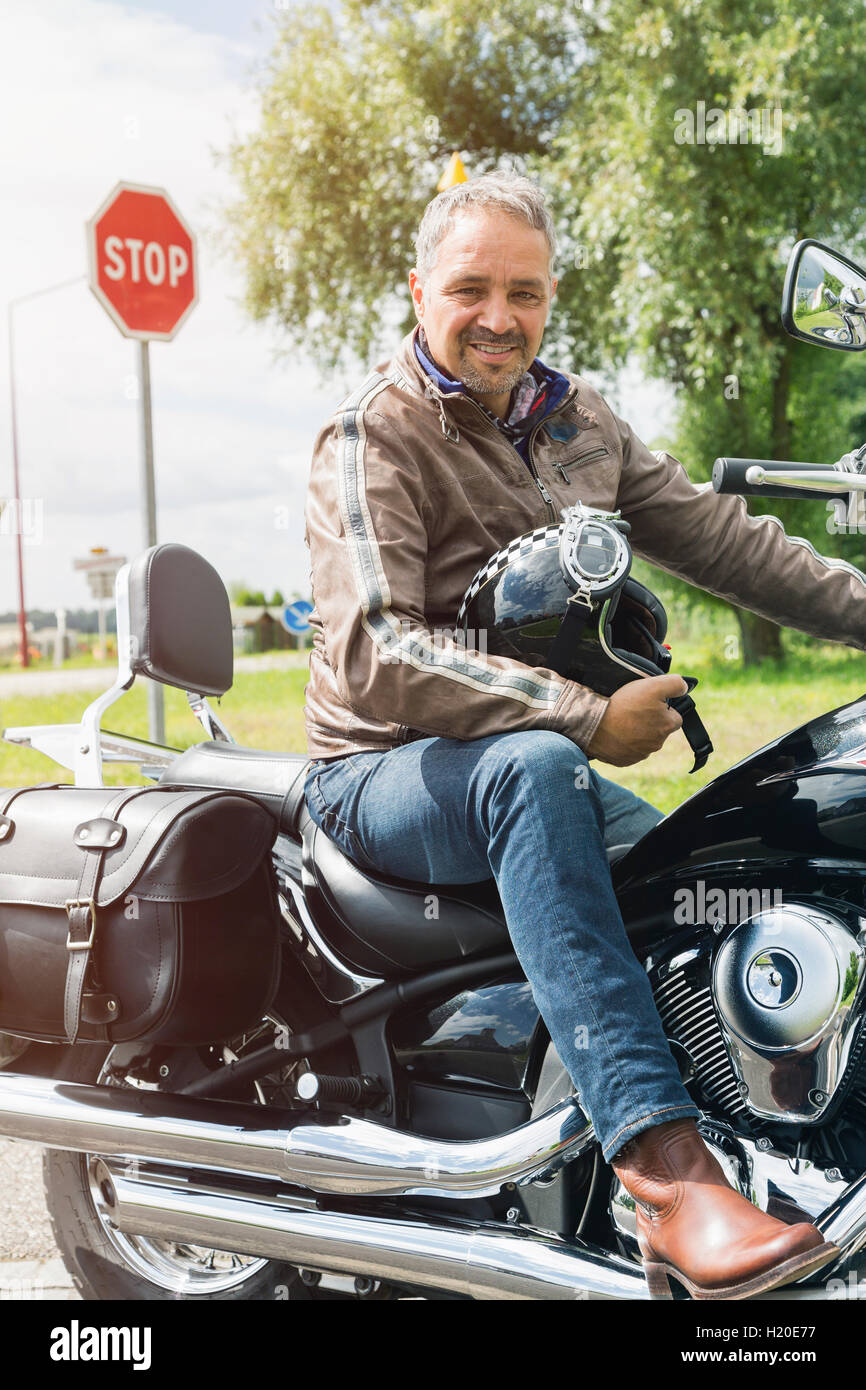 Portrait of man sitting on his motorbike Stock Photo - Alamy