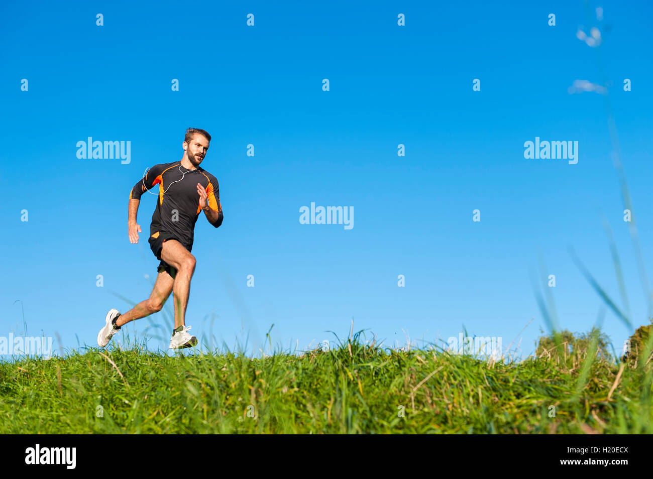 Man running on meadow under blue sky Stock Photo - Alamy