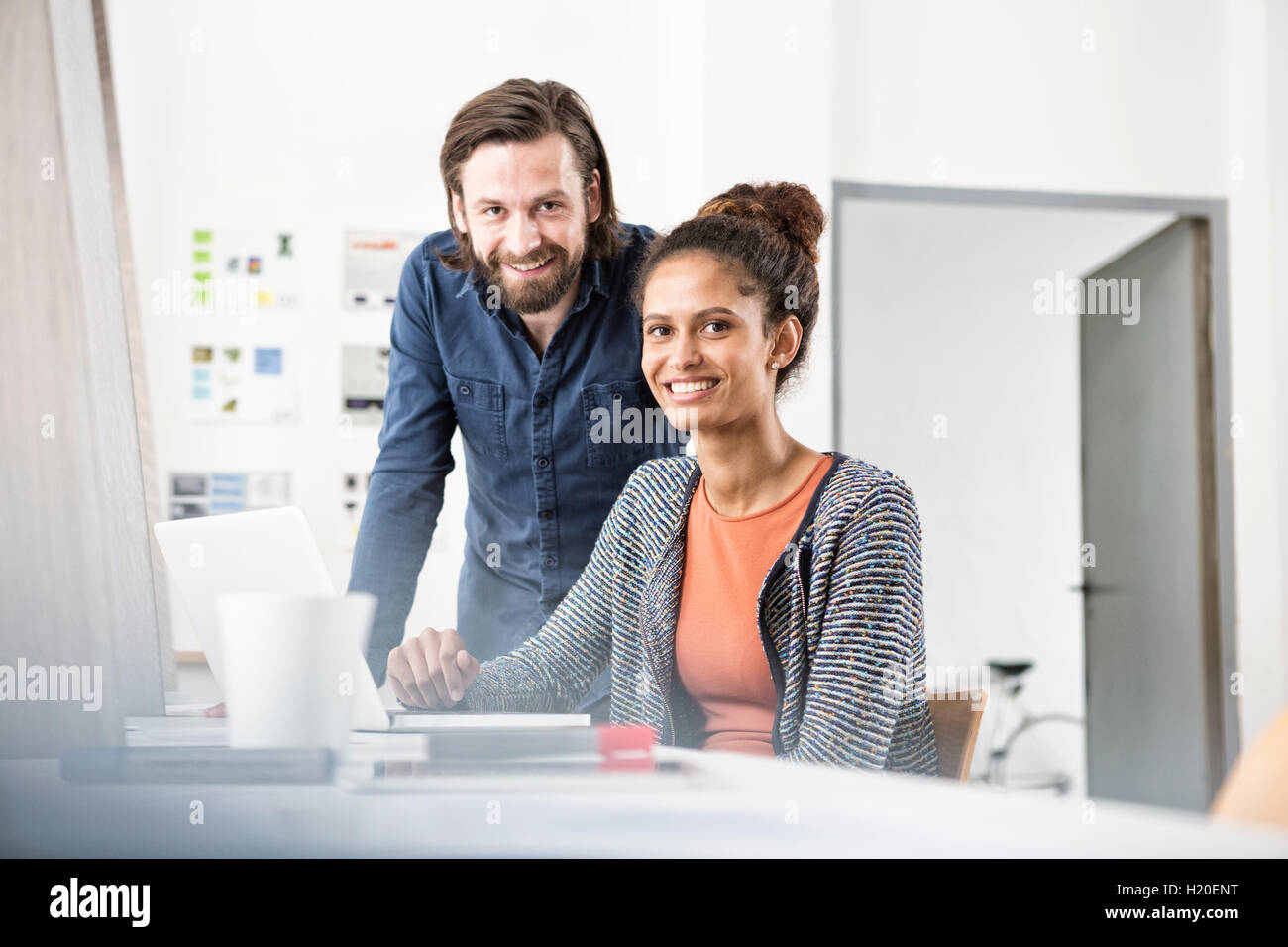 Portrait of two smiling colleagues at office desk Stock Photo - Alamy