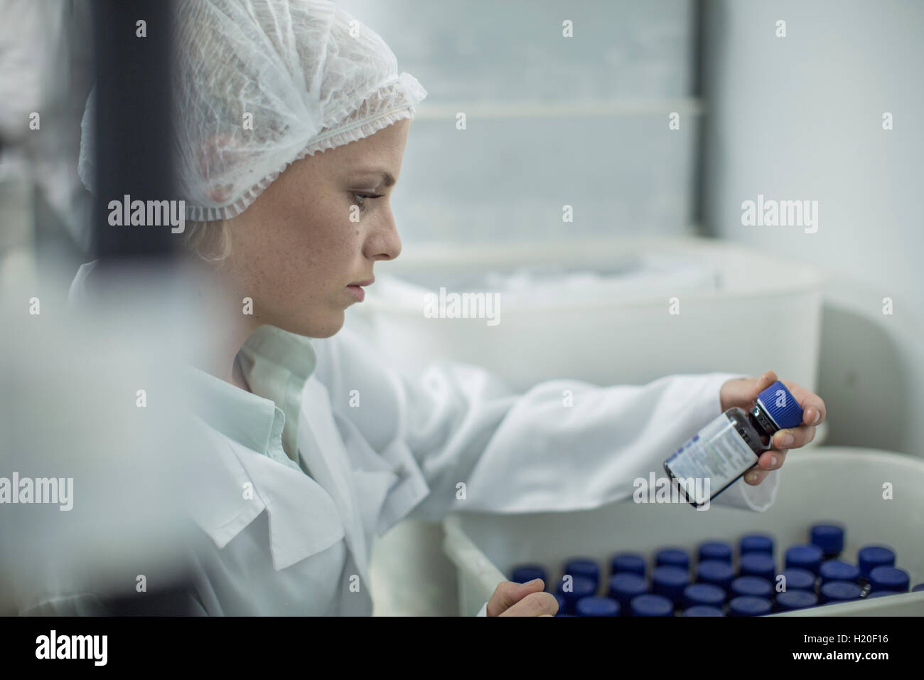 Lab worker in pharmaceutical plant looking at pill bottle Stock Photo ...