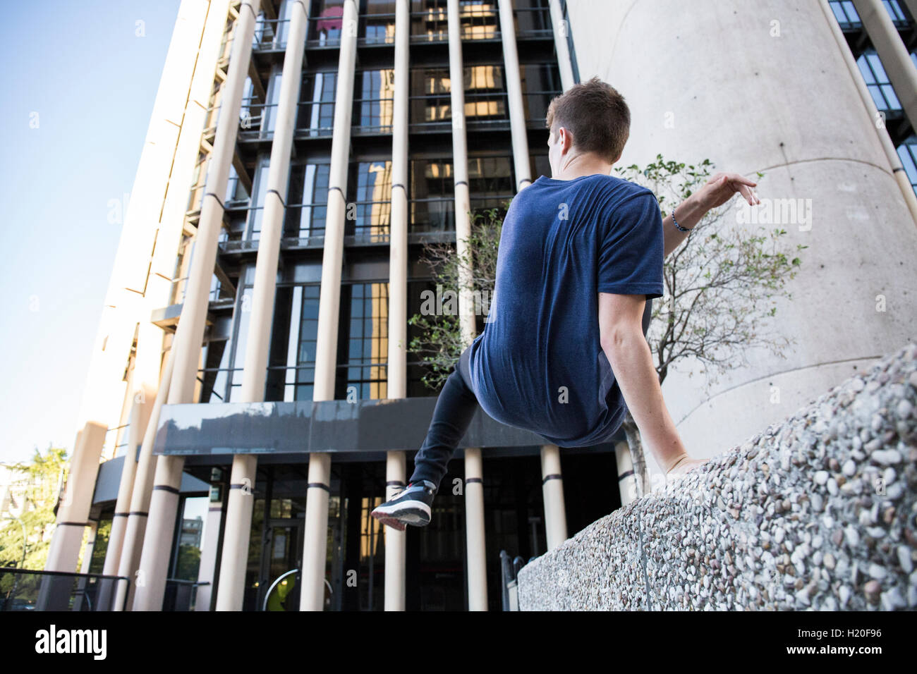 Spain, Madrid, man jumping over a wall in the city during a parkour ...