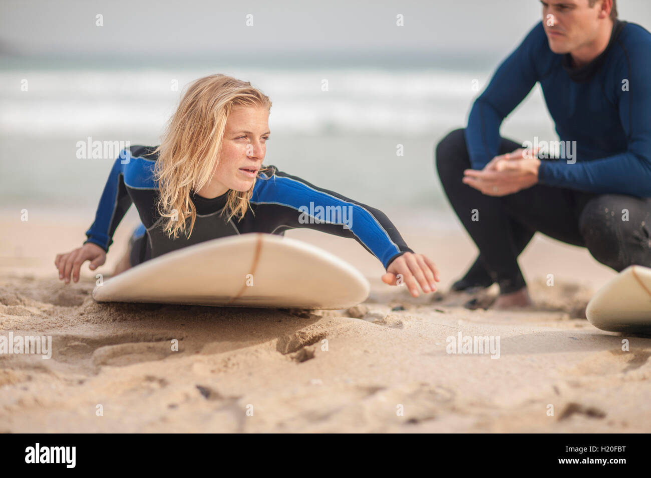 Man instructing woman on surfboard on the beach Stock Photo - Alamy