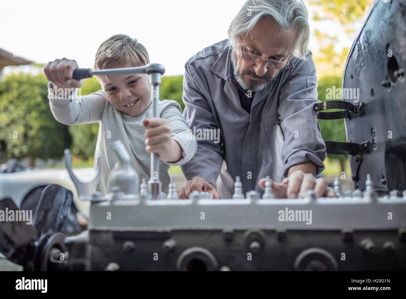 Senior man and boy working on mechanism of a car Stock Photo - Alamy