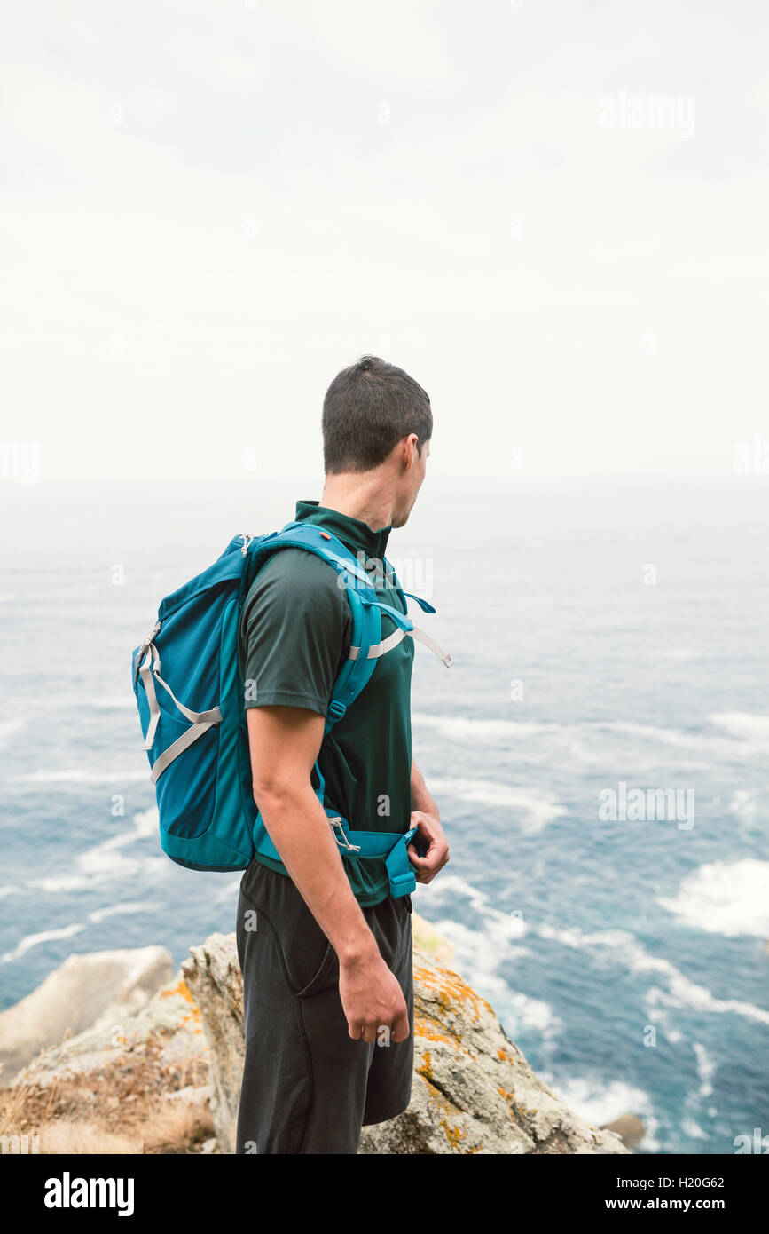 Young man with a backpack in front of the sea at the coast Stock Photo ...