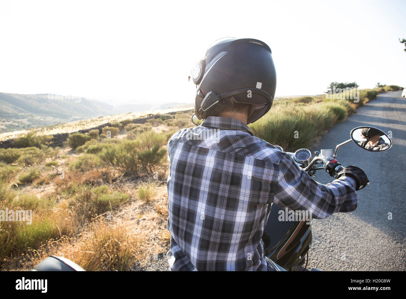 Back view of man on motorbike looking at view Stock Photo - Alamy