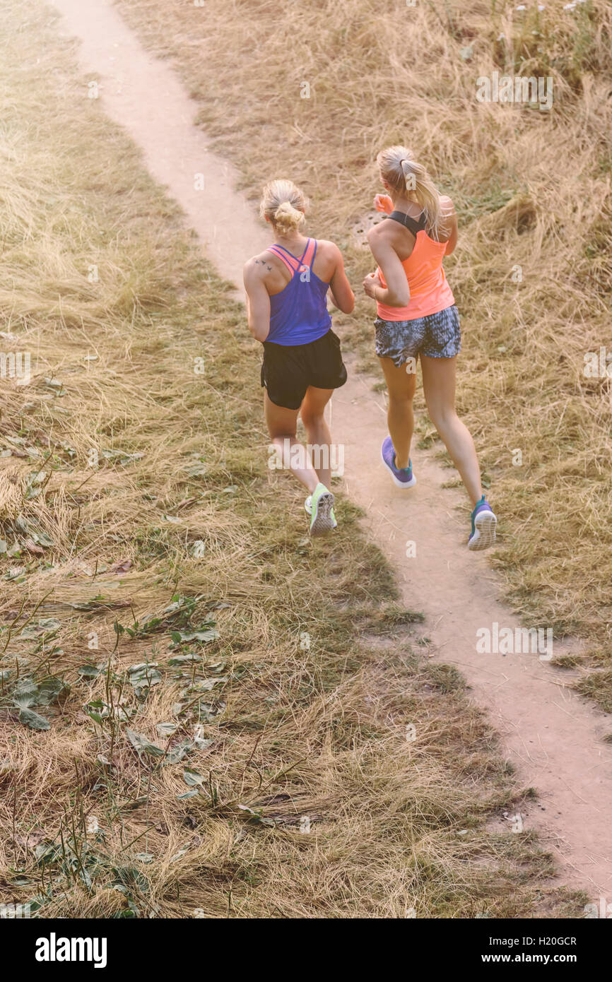 Two young women running on field path Stock Photo - Alamy