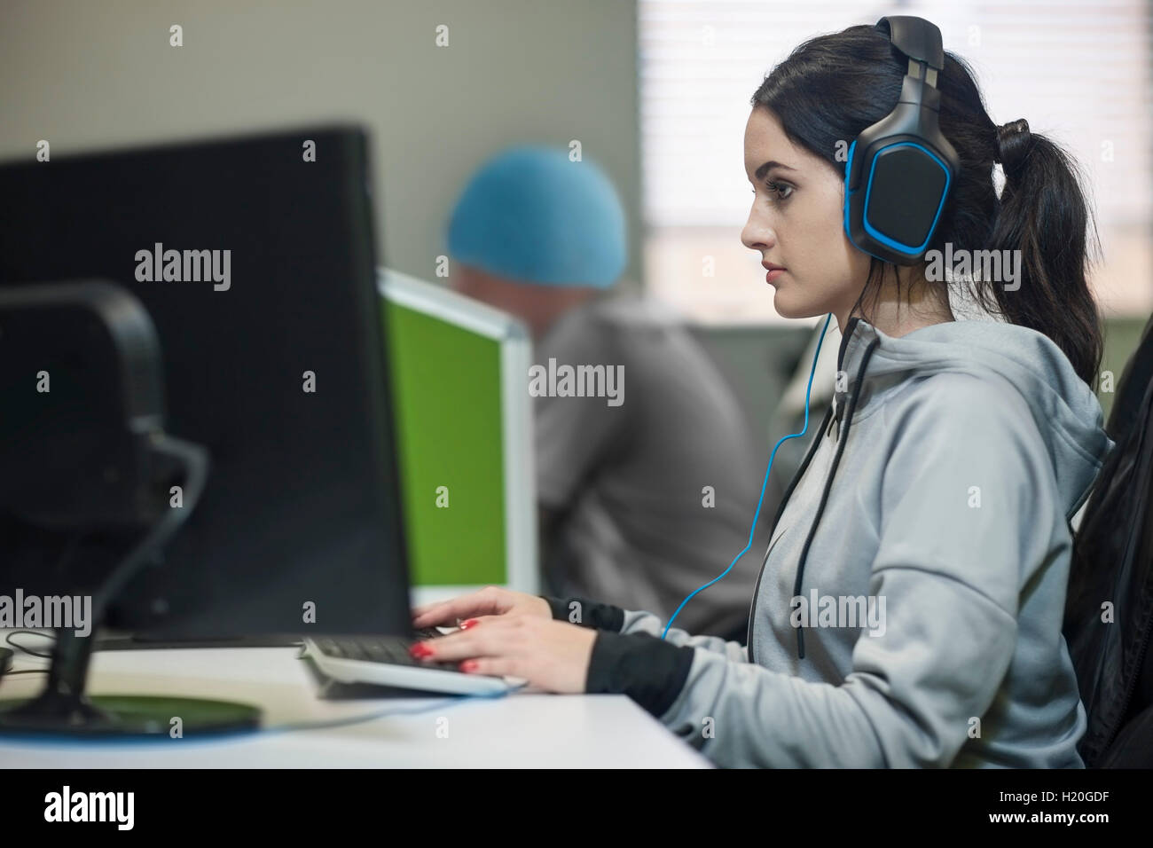 Young woman wearing headphones working on computer in office cubicle Stock Photo - Alamy