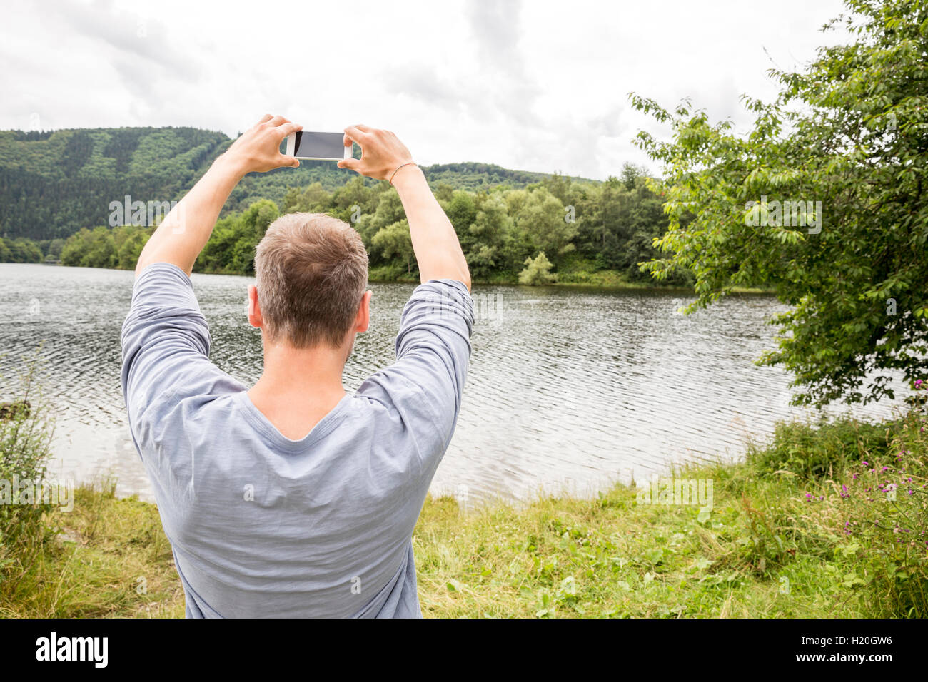 Man taking a cell phone picture at lakeside Stock Photo - Alamy