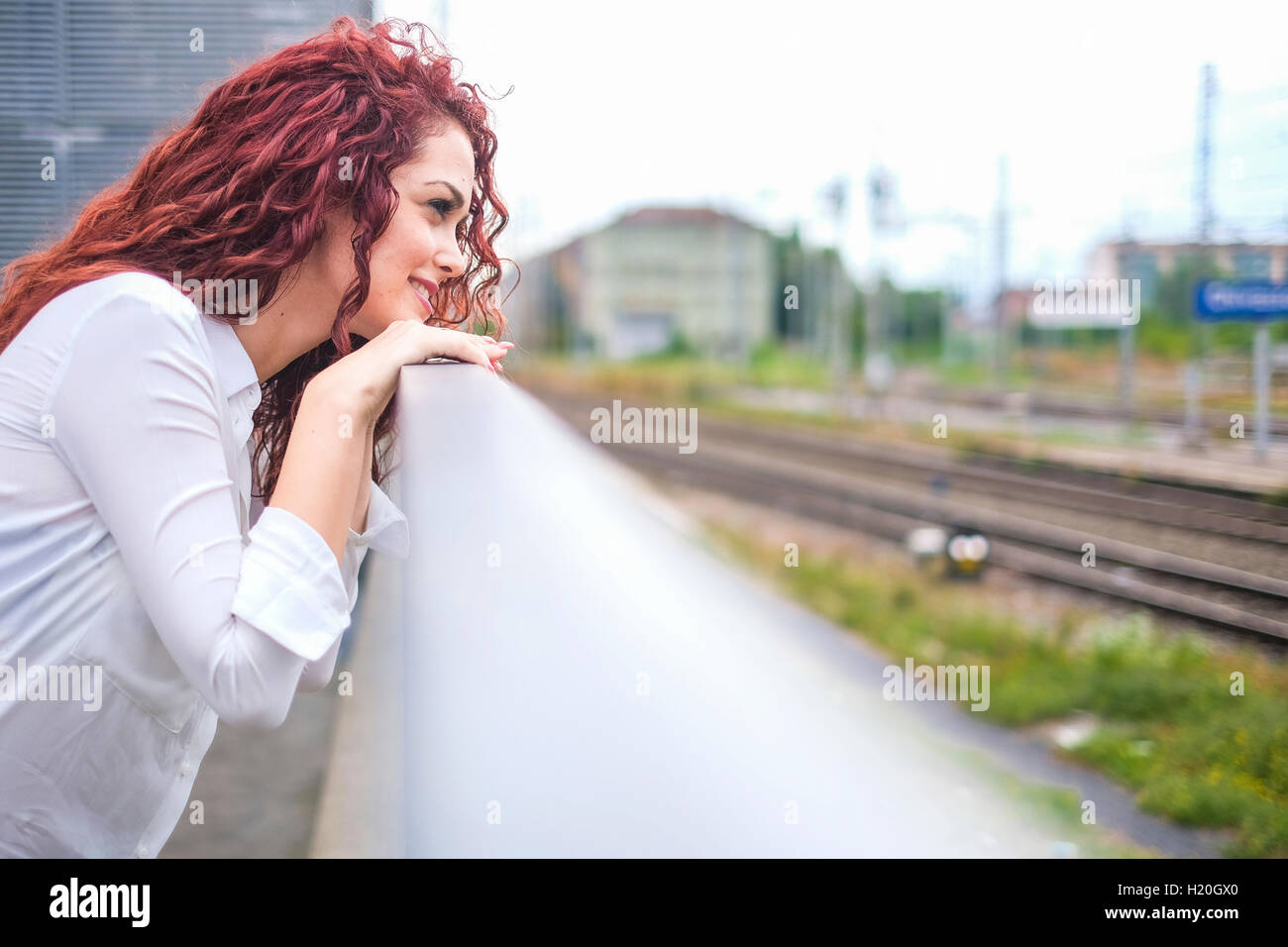 Redheaded young woman leaning on railing looking at distance Stock ...