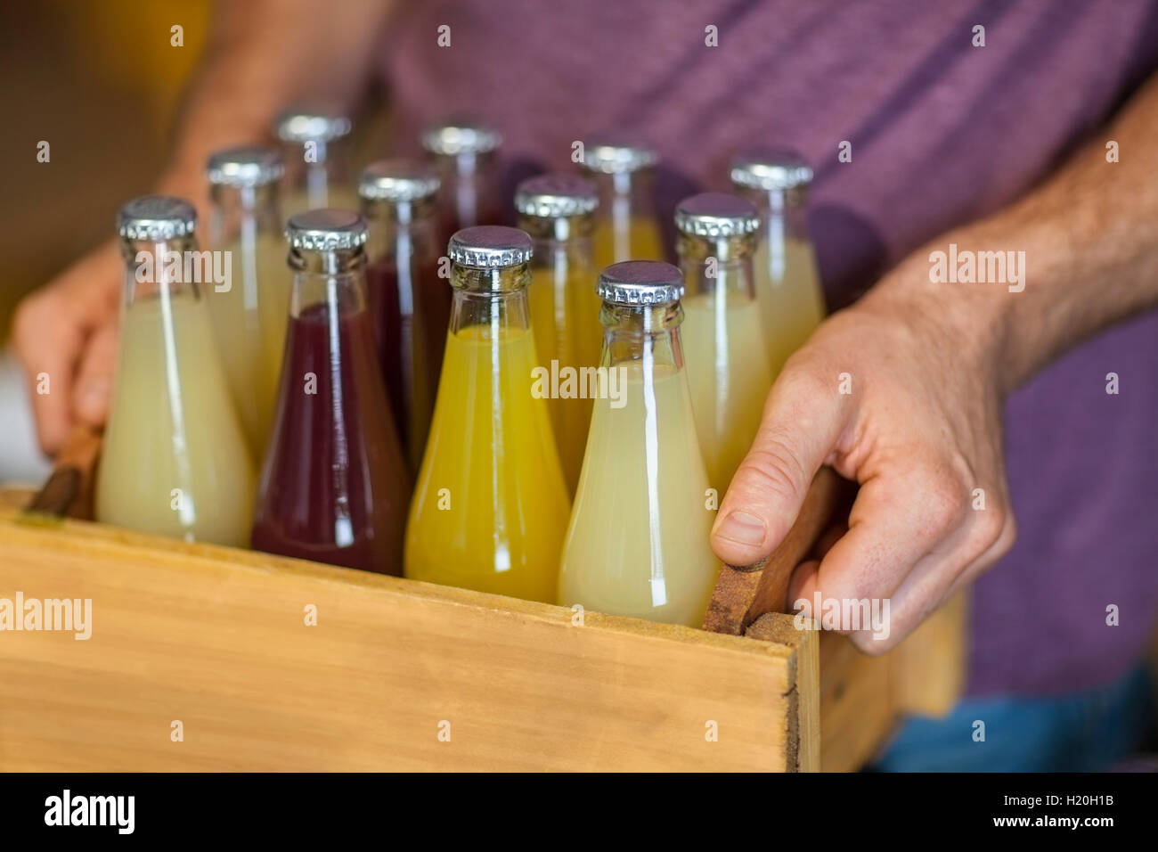 Man carrying wooden box with various bottles of juice in warehouse ...