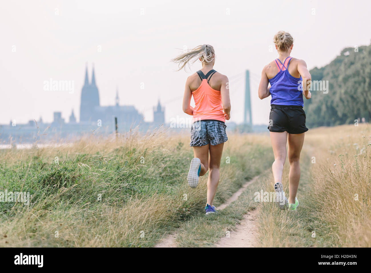 Two young women running on field path Stock Photo - Alamy