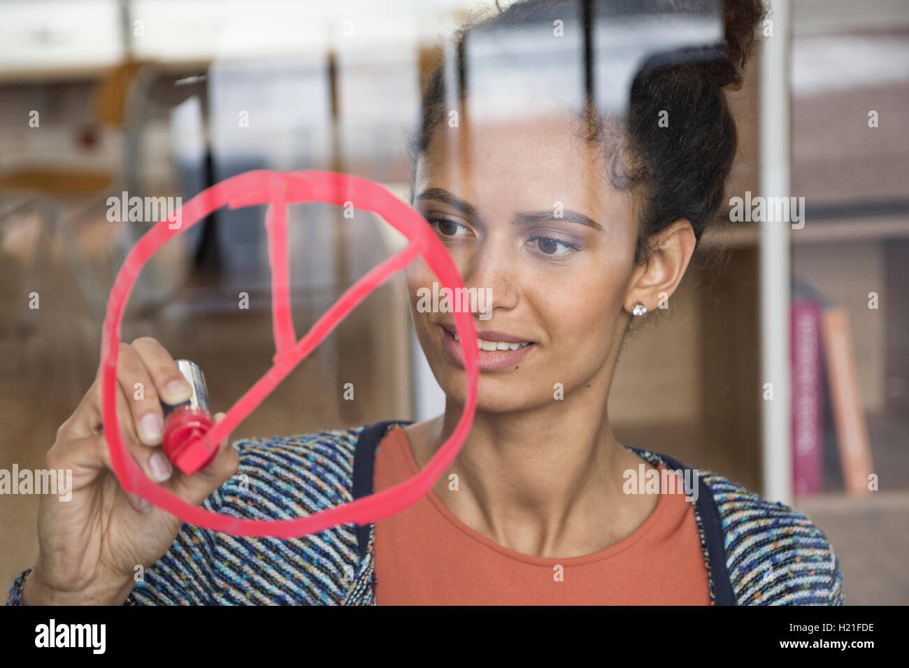 Woman drawing symbol on glass pane in office Stock Photo - Alamy