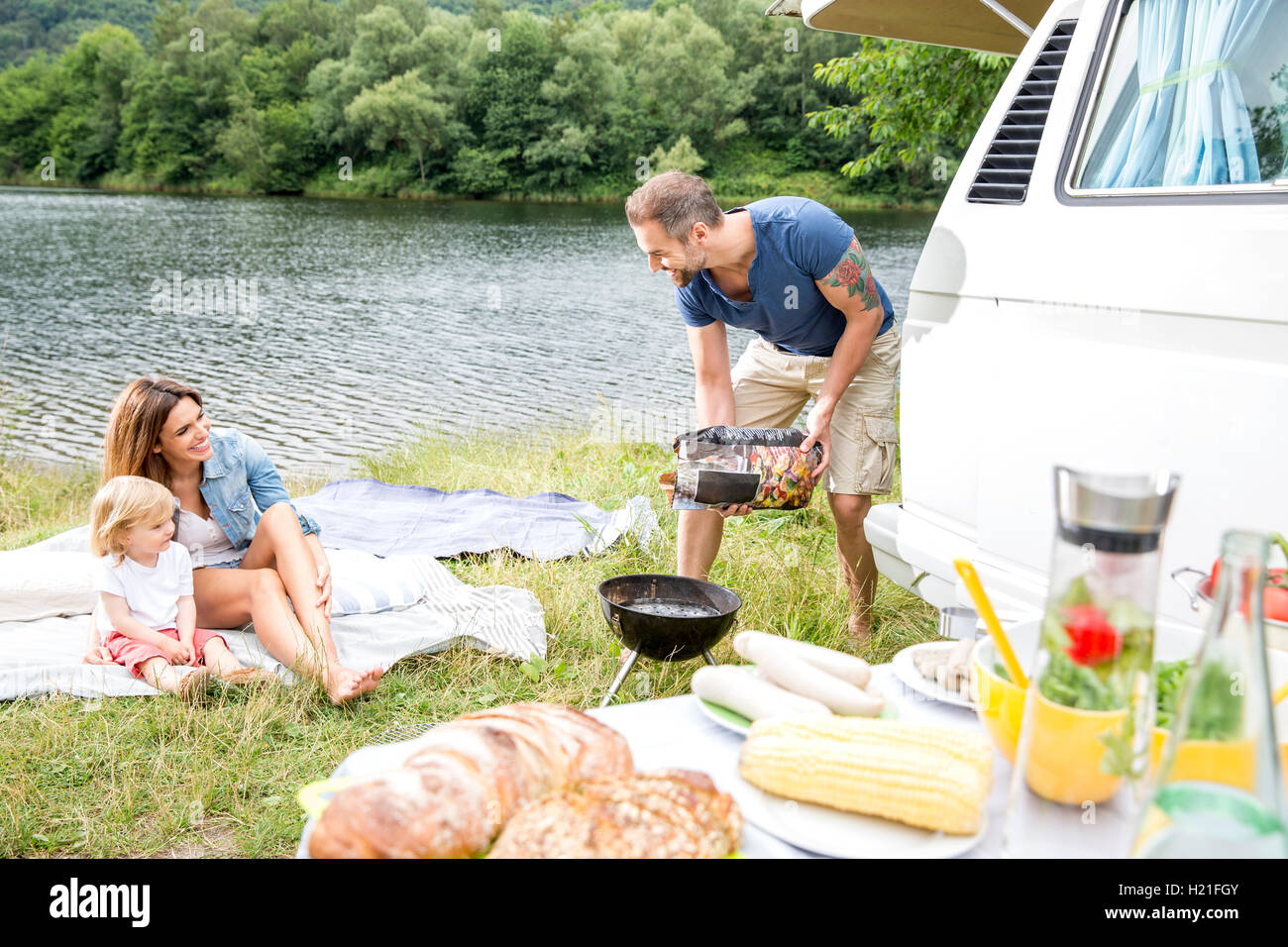 Happy family having barbecue at lakeside Stock Photo - Alamy