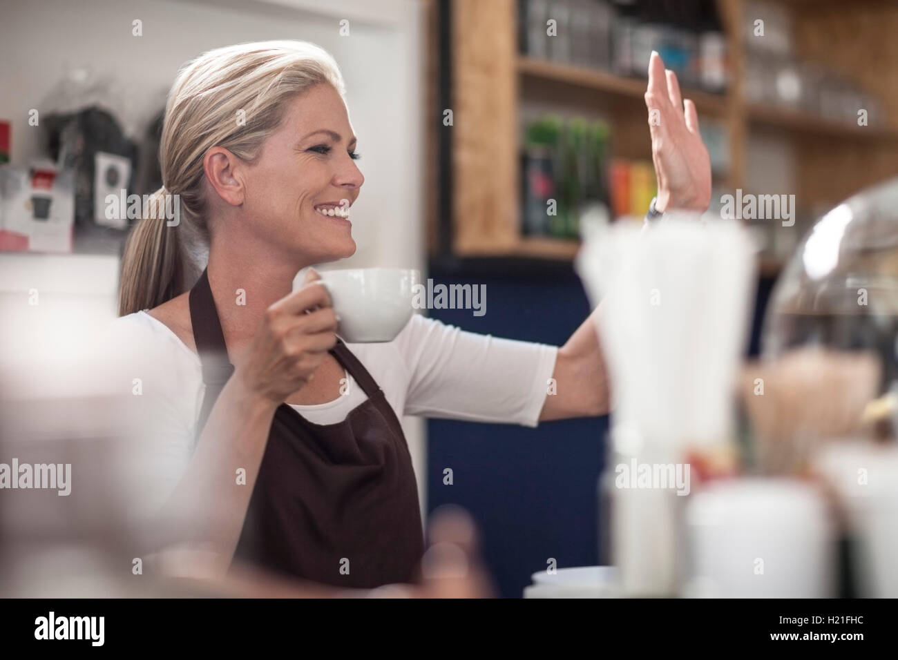 Smiling female barista waving Stock Photo - Alamy