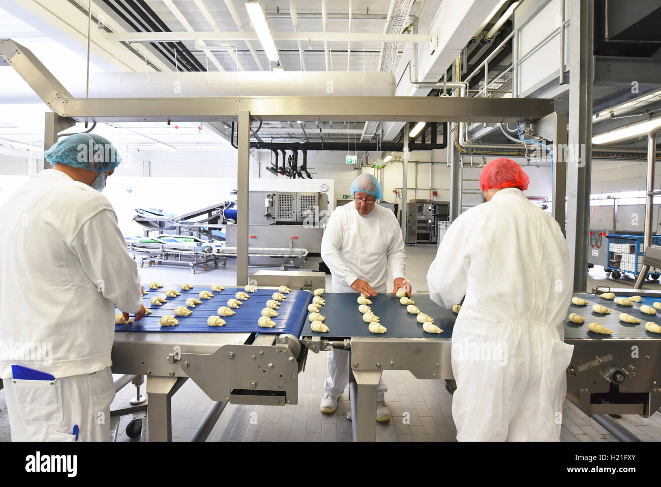 Workers at production line in a baking factory with croissants Stock ...