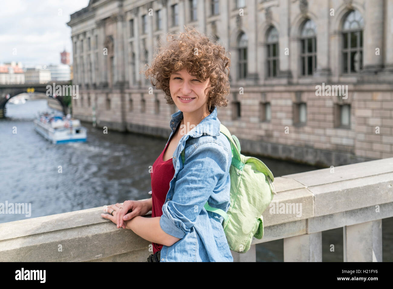 Germany, Berlin, portrait of smiling young woman standing in front of ...