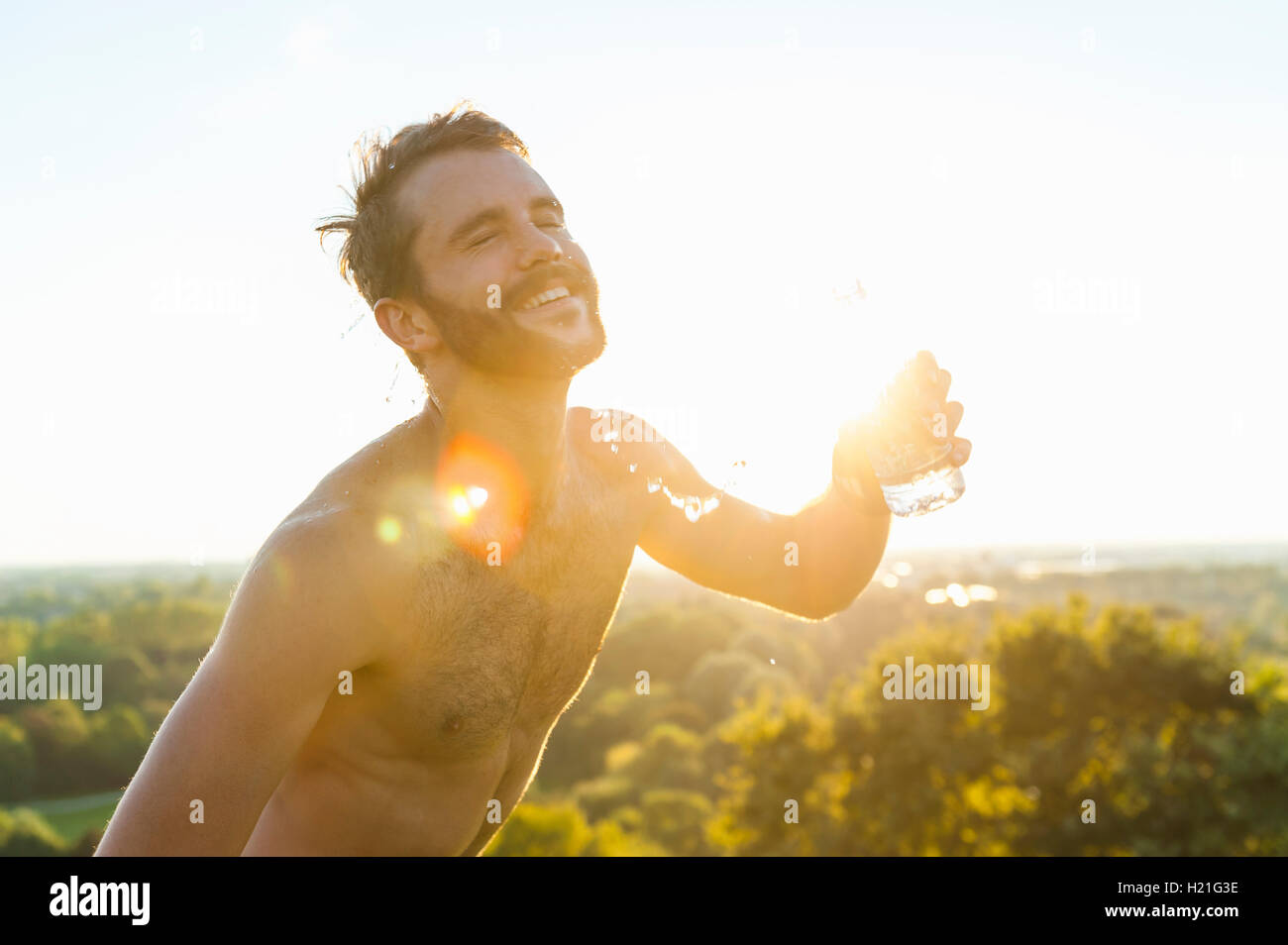 Happy barechested athlete pouring water over his body at sunset Stock ...