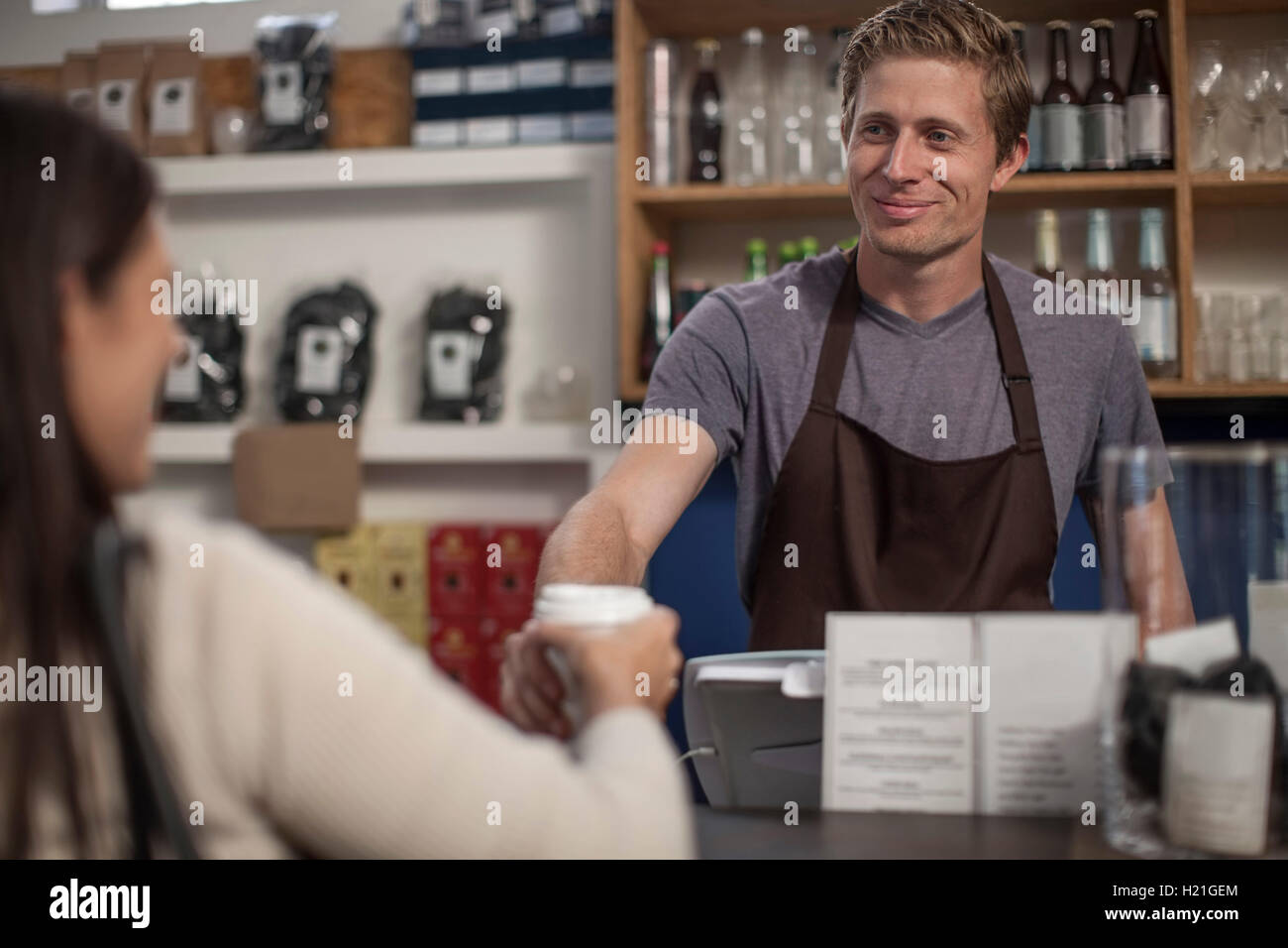 Man in a cafe handing over disposable coffee cup Stock Photo - Alamy