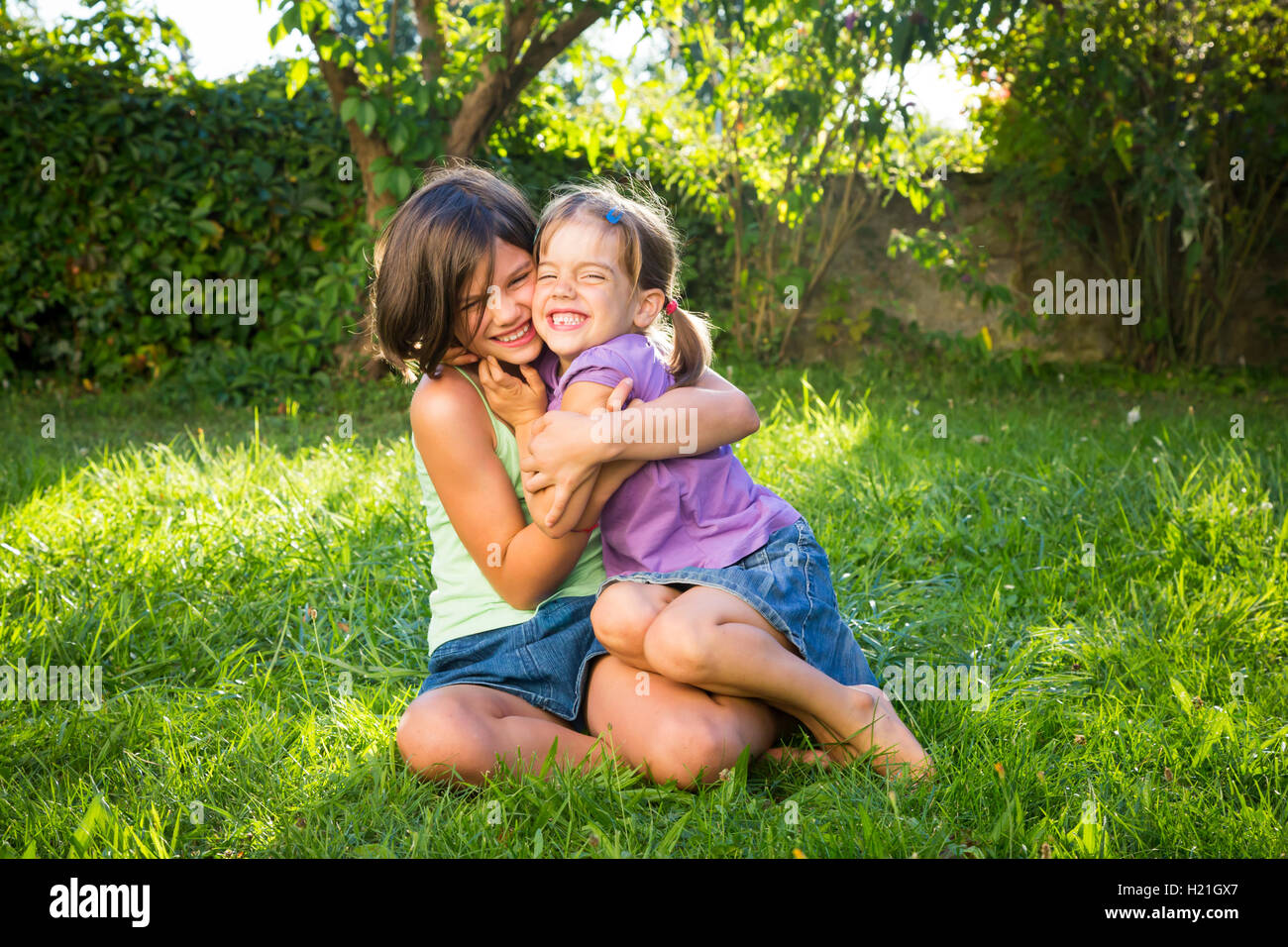 Two sisters having fun ogether on a meadow Stock Photo - Alamy