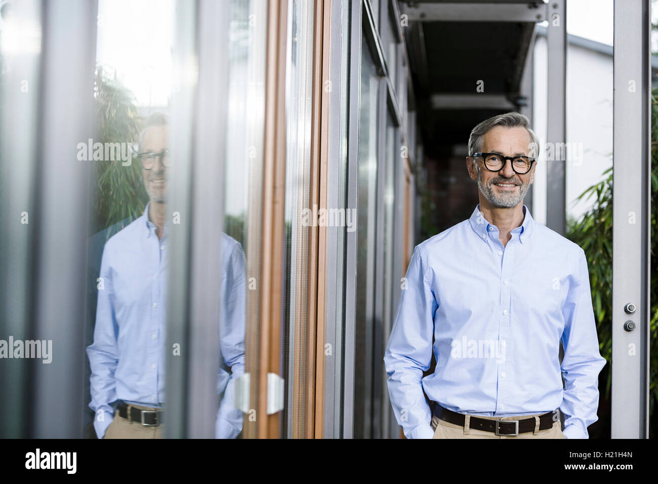 Portrait of smiling man reflecting at facade of his house Stock Photo ...