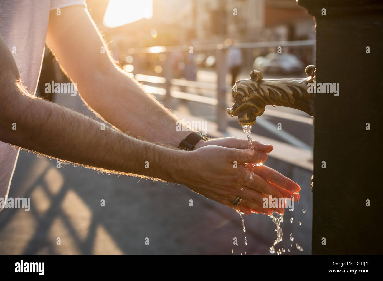 Young man refreshing himself in the city, partial view Stock Photo - Alamy