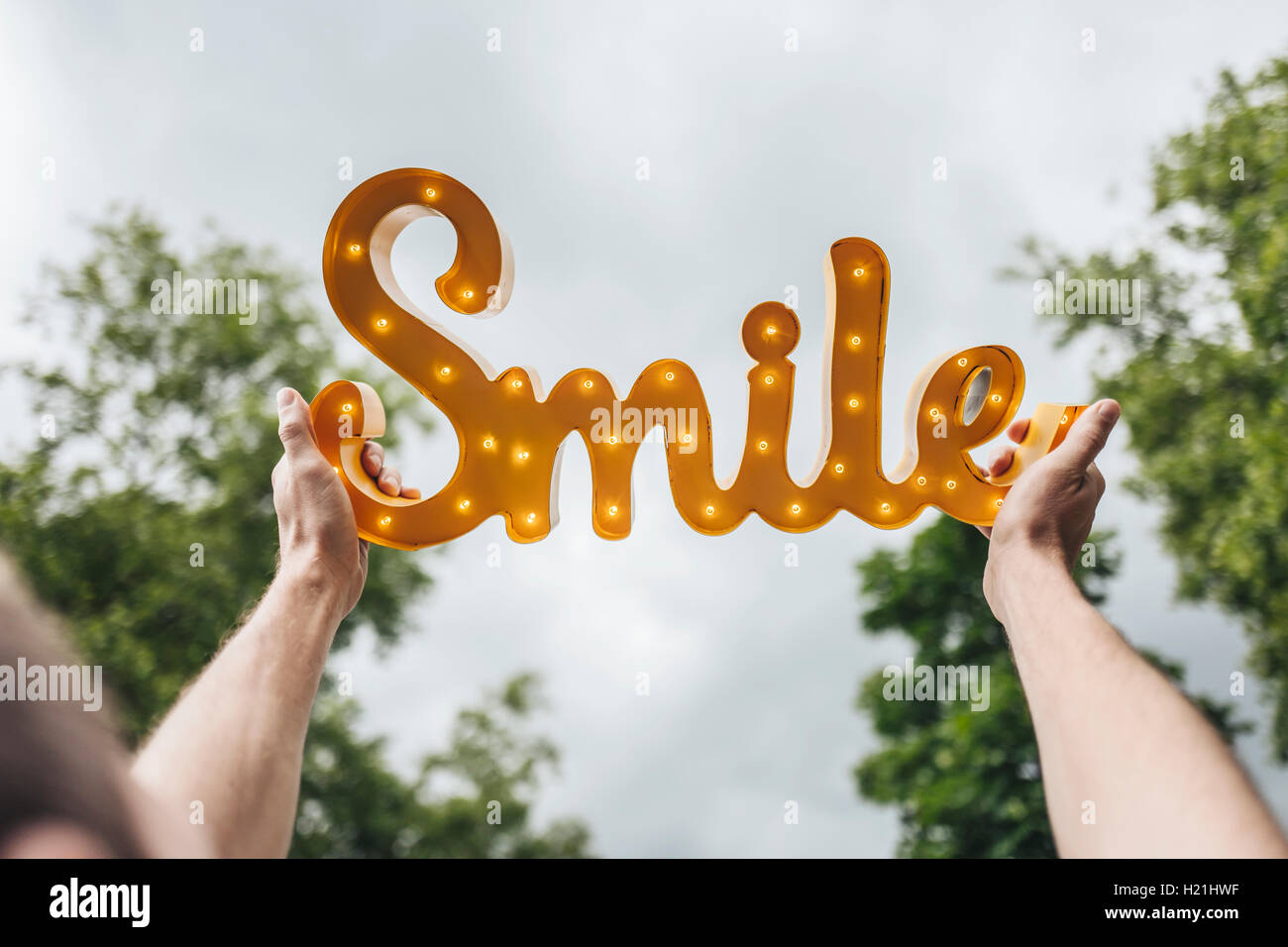 Man holding aloft the shining word 'Smile' Stock Photo - Alamy
