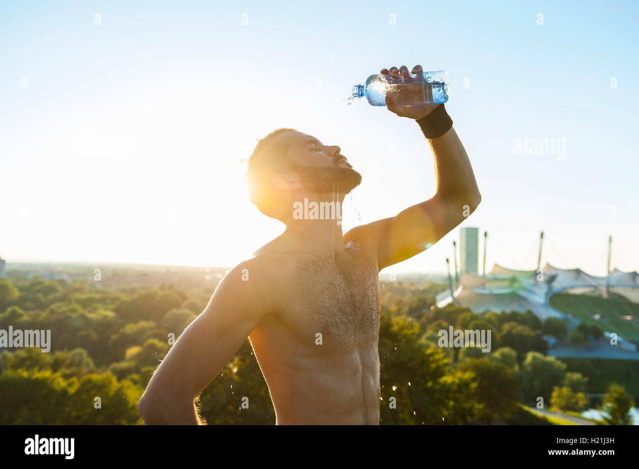 Barechested athlete pouring water over his face at sunset Stock Photo ...