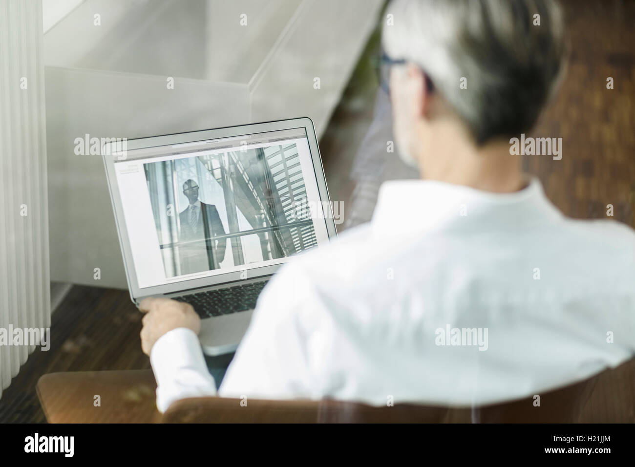 Back view of man looking at laptop Stock Photo - Alamy