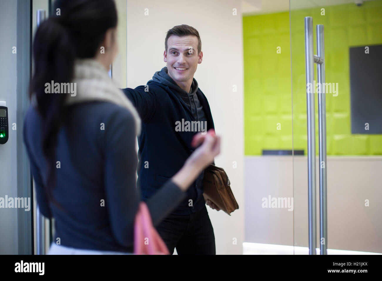 Smiling man opening door for young woman Stock Photo - Alamy