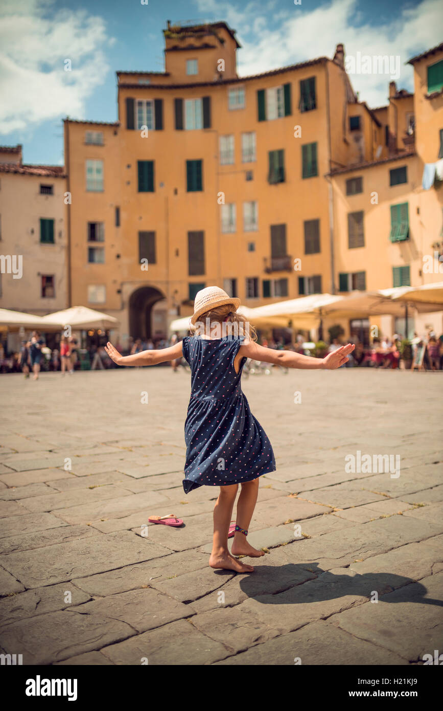Italy, Lucca, back view of little girl dancing at the Piazza dell ...