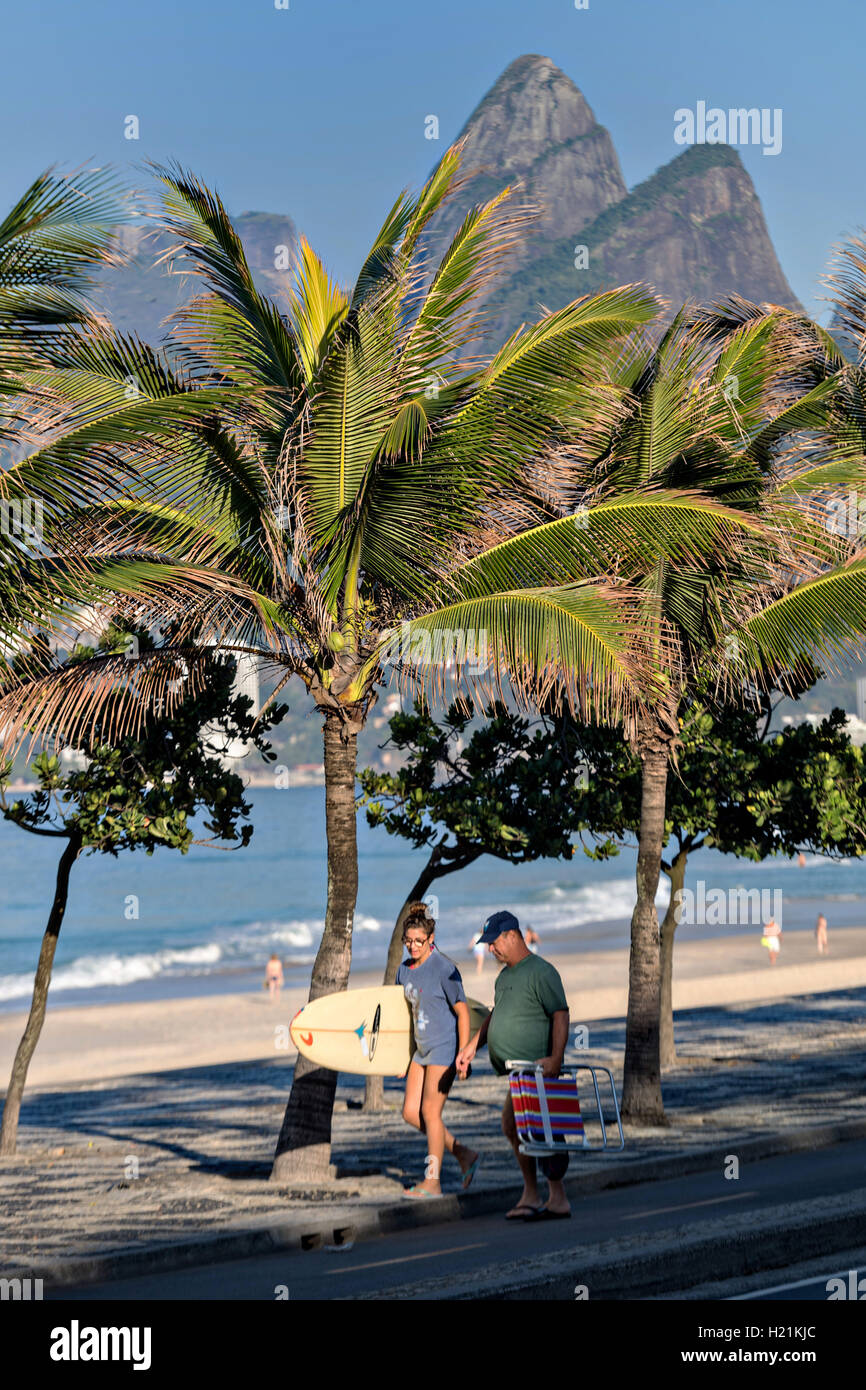 Beach goers walk along Ipanema beach past Two Brothers Mountain early ...