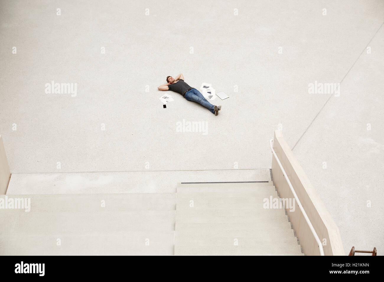 Young man lying on floor surrounded by papers Stock Photo - Alamy