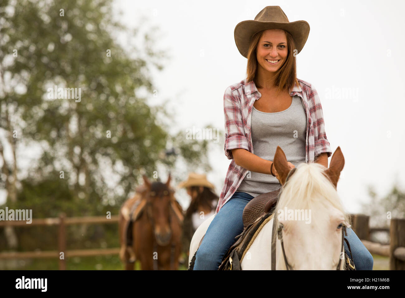 Young woman riding horse at riding stable Stock Photo - Alamy
