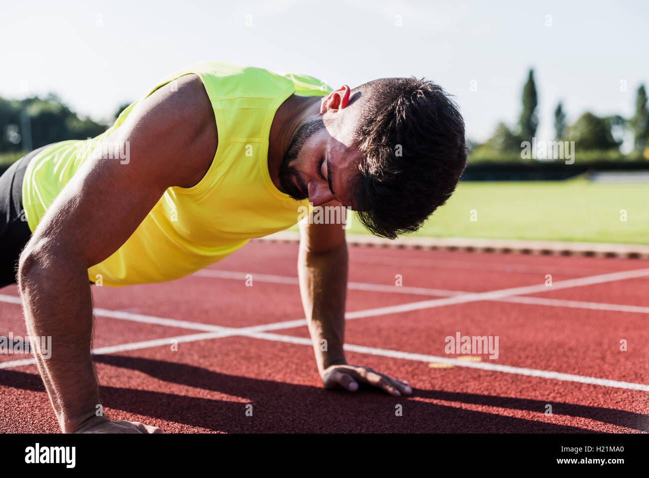 Athlete doing pushu-ups on tartan track Stock Photo - Alamy