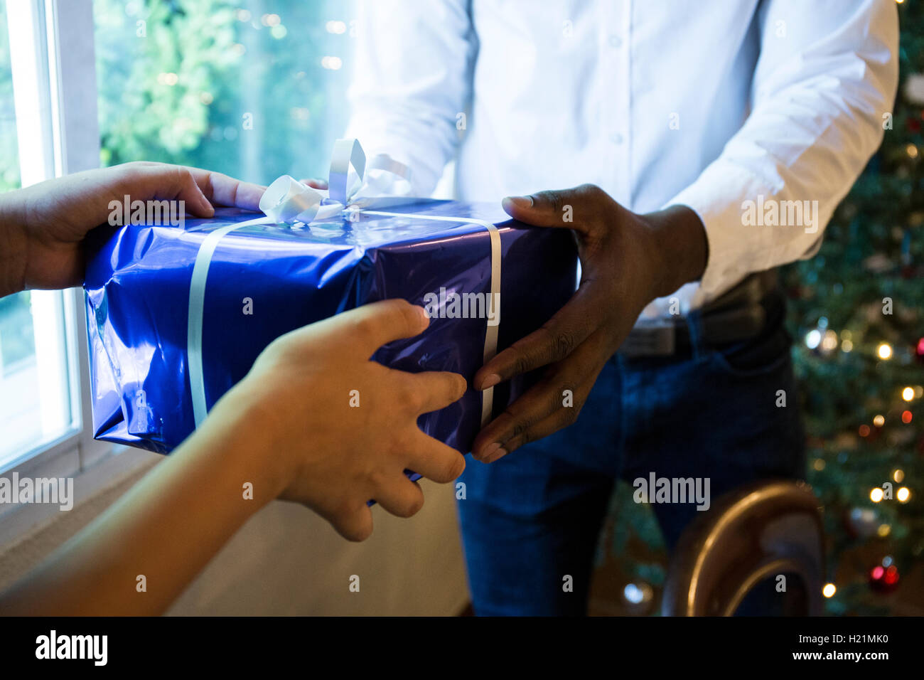 Close-up of man handing over Christmas present to woman Stock Photo - Alamy