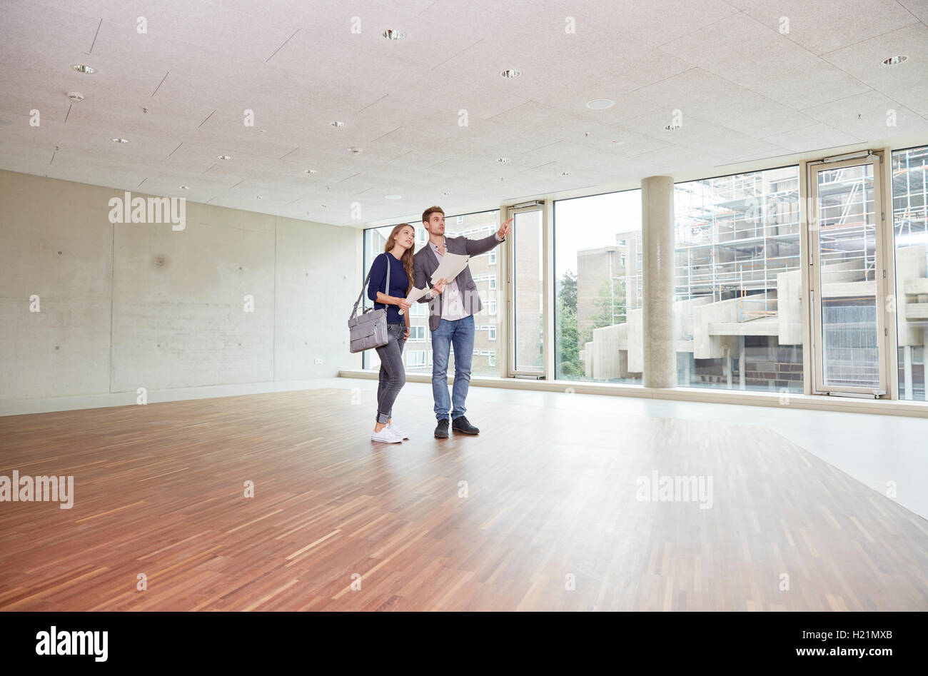 Young man and woman with documents talking in empty room Stock Photo ...