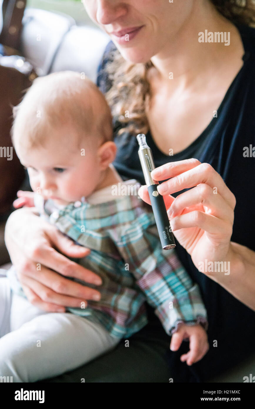 Woman smoking electronic cigarette beside a baby Stock Photo - Alamy