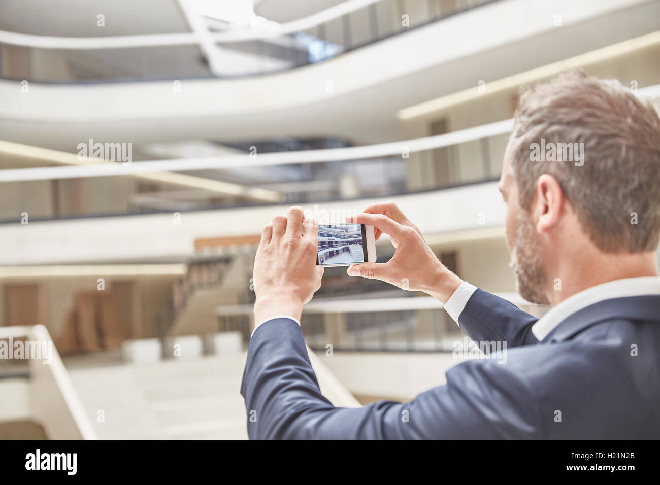 Businessman taking cell phone picture in modern office building Stock ...