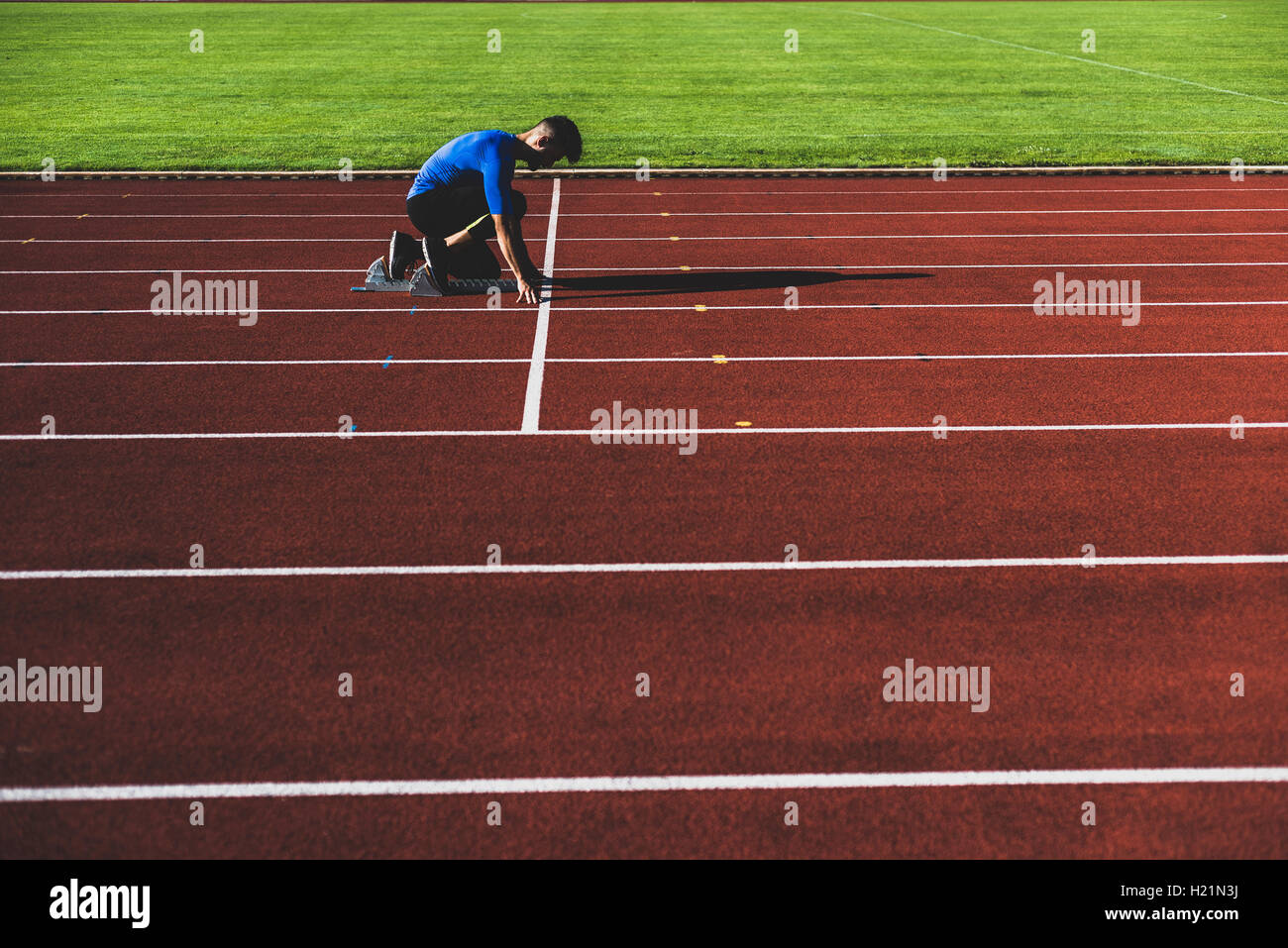 Runner on tartan track in starting position Stock Photo - Alamy