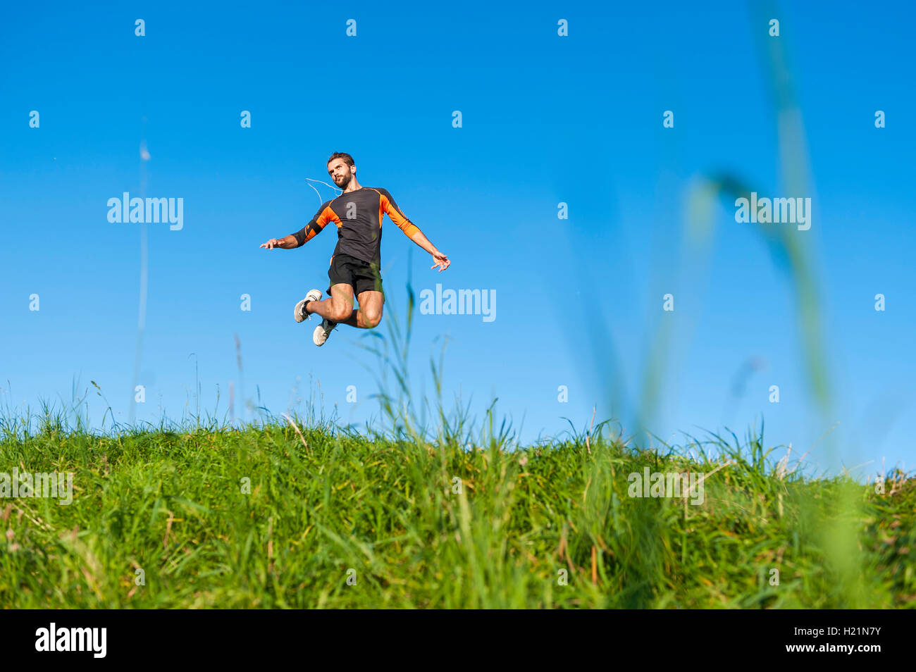 Athlete jumping on meadow under blue sky Stock Photo - Alamy