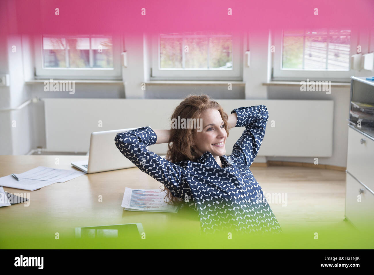 Smiling woman in office leaning back Stock Photo - Alamy