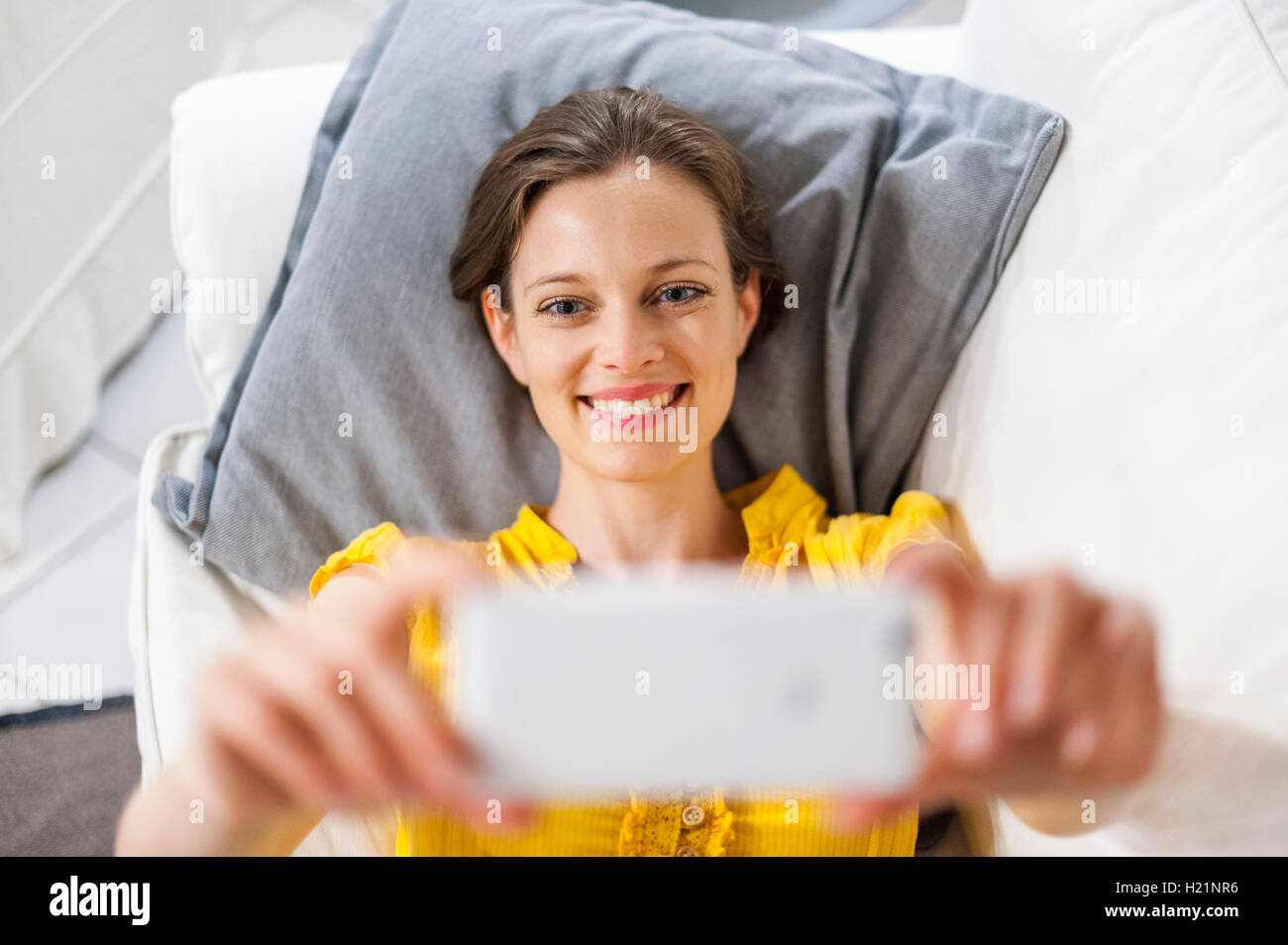 Woman lying on couch taking selfie Stock Photo - Alamy