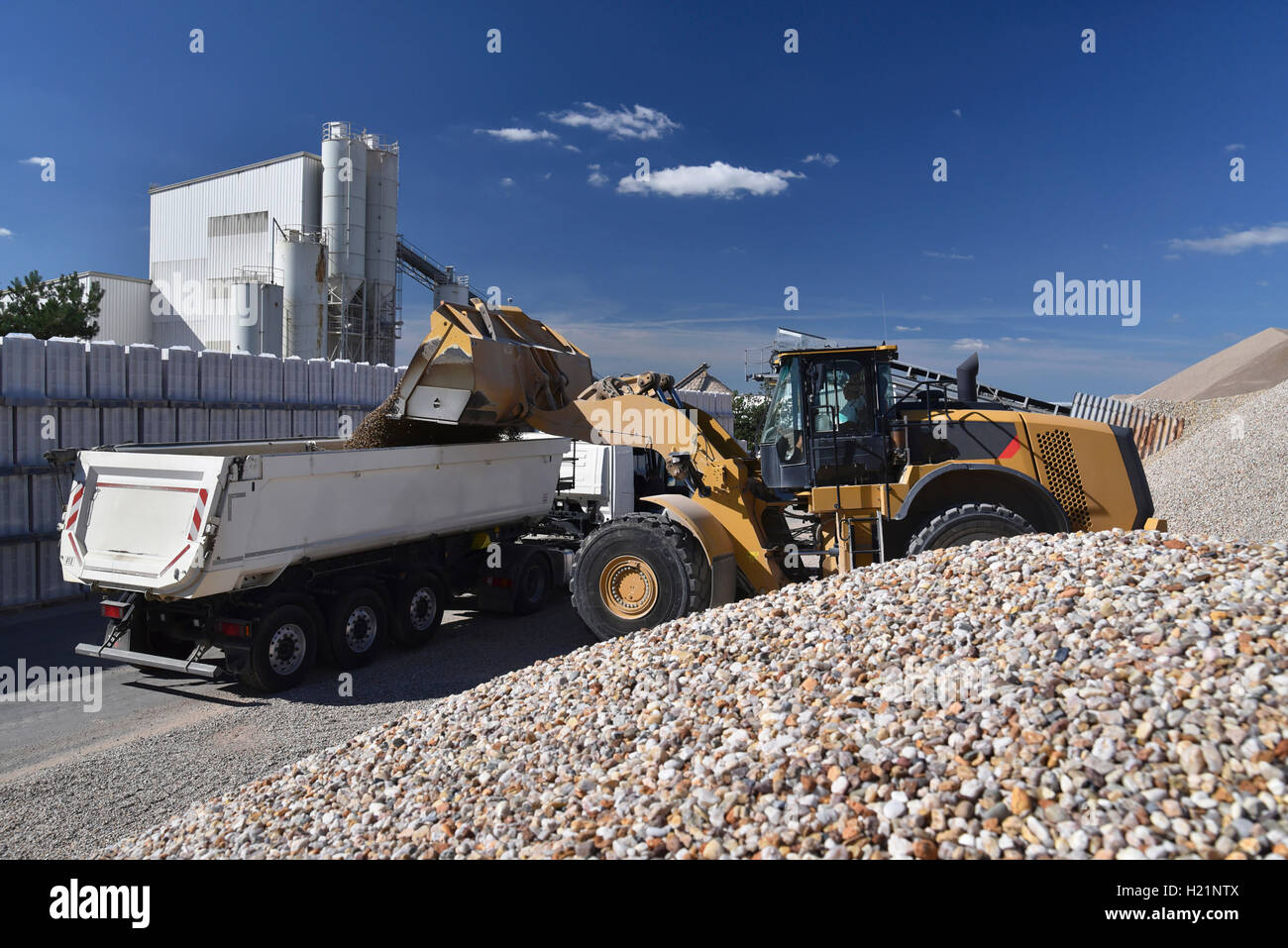 Wheel loader loading gravel on truck Stock Photo - Alamy