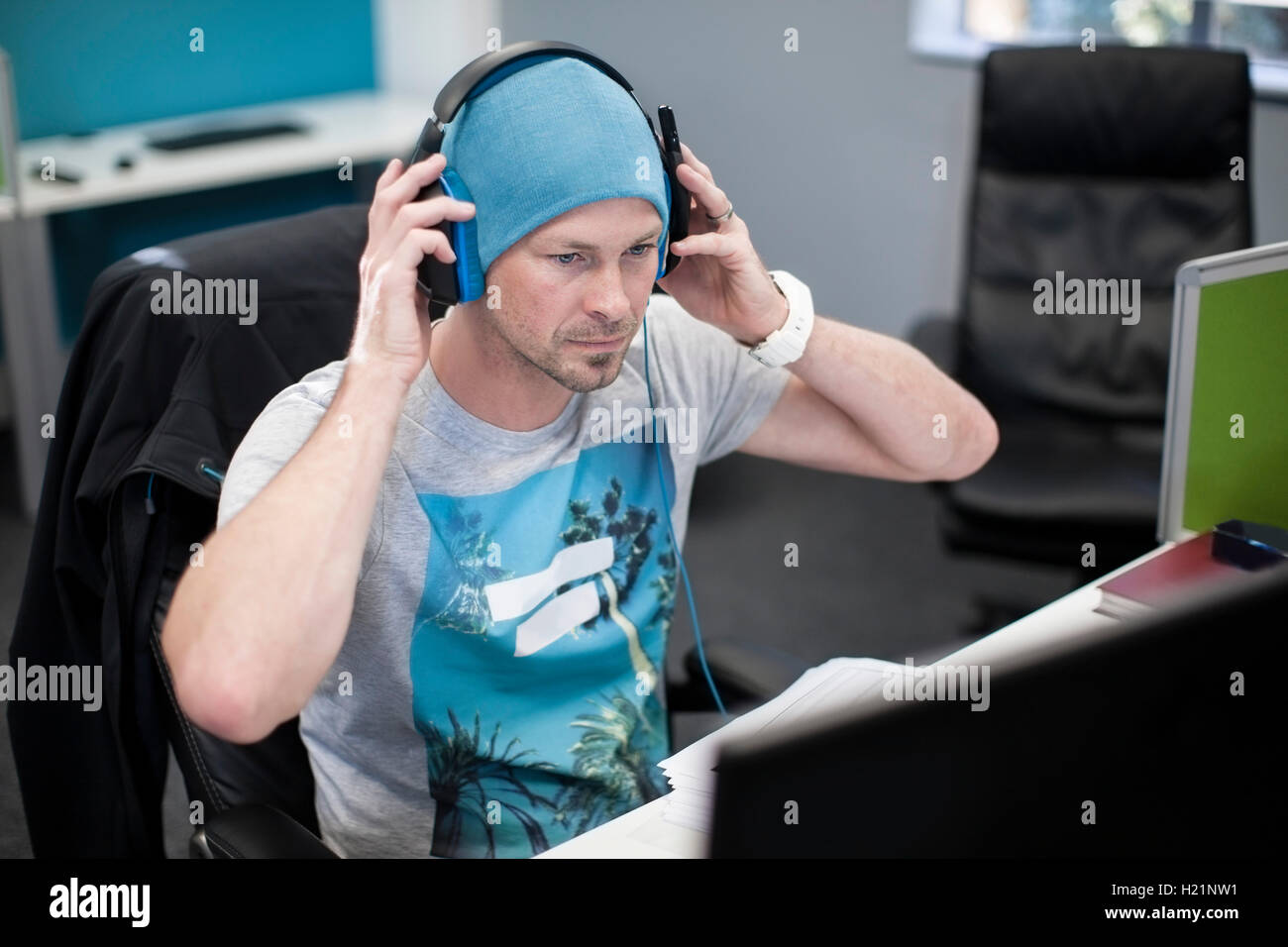 Young man wearing headphones working on computer in office Stock Photo ...