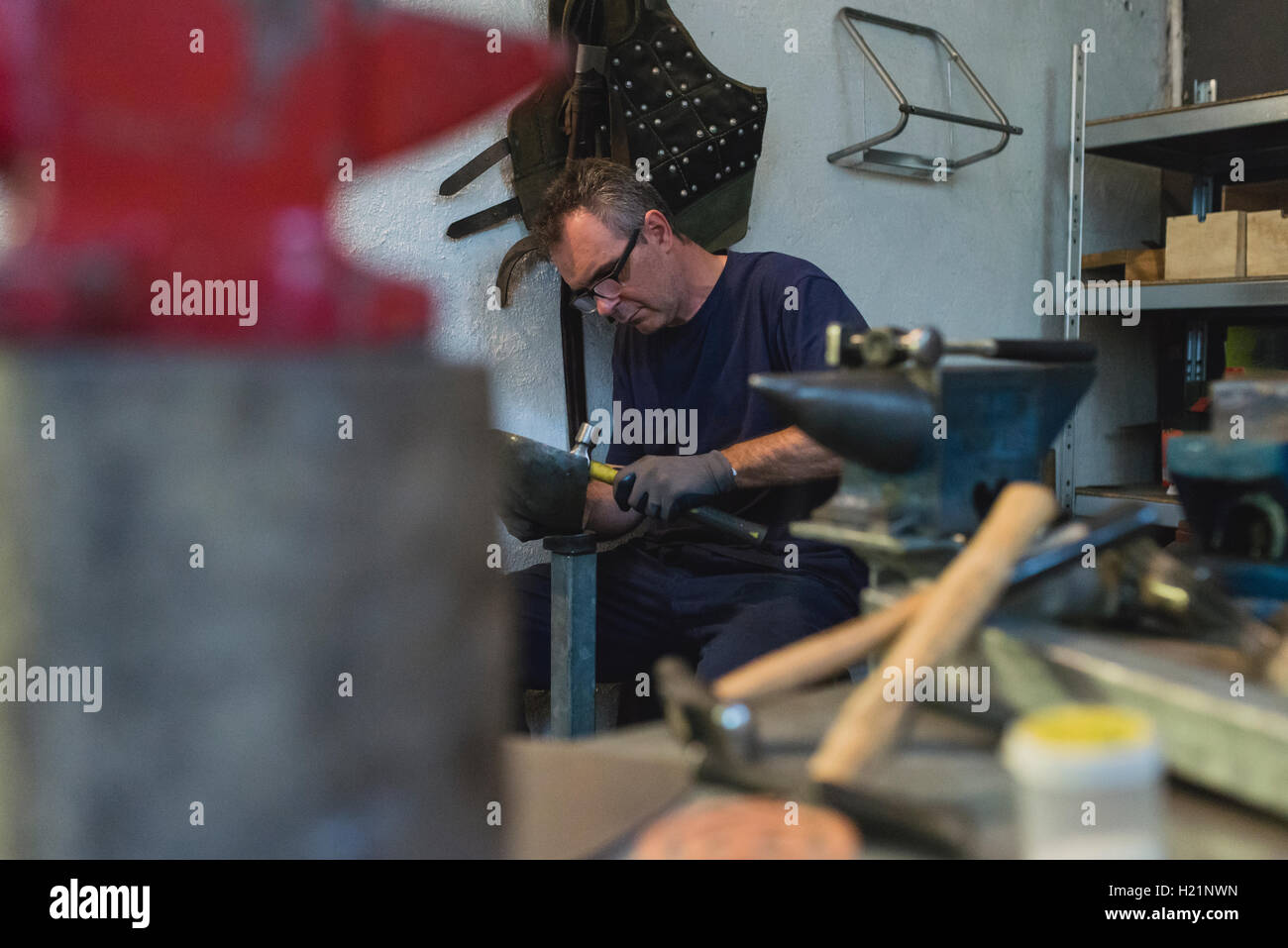 Forger hammering metal in workshop Stock Photo - Alamy