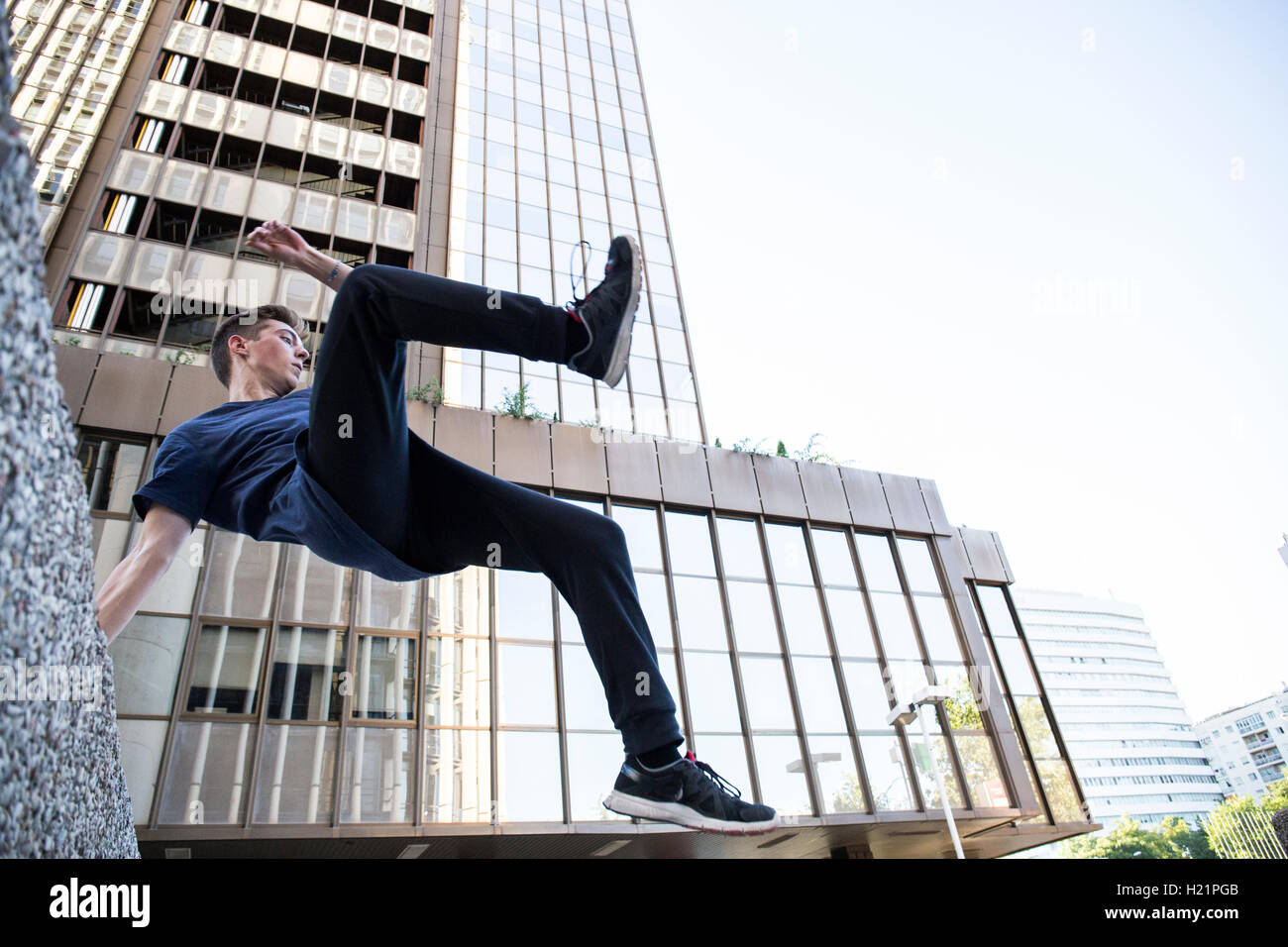 Spain, Madrid, man jumping over a wall in the city during a parkour ...
