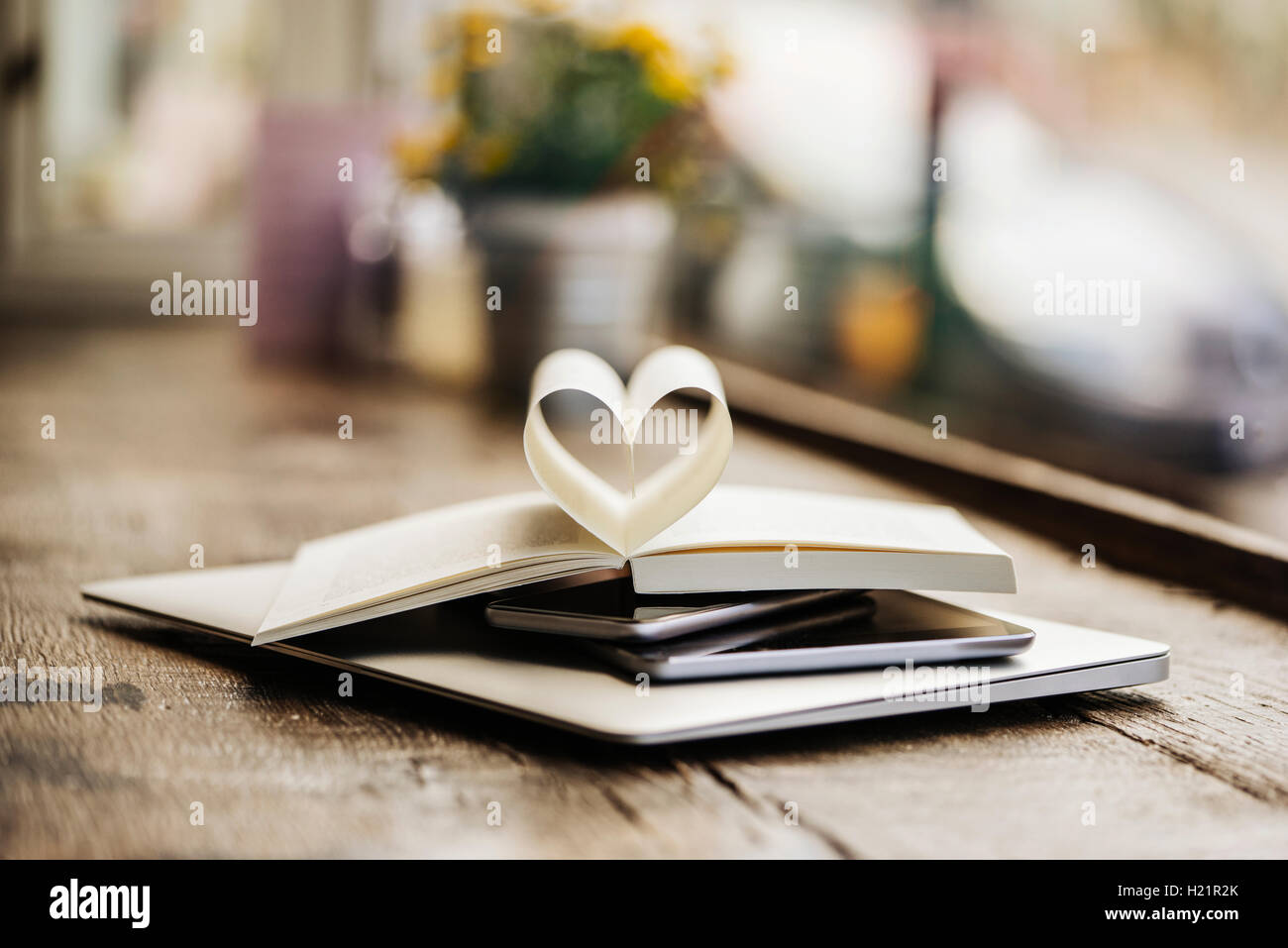 Book with heart-shaped pages on stack of mobile devices Stock Photo - Alamy