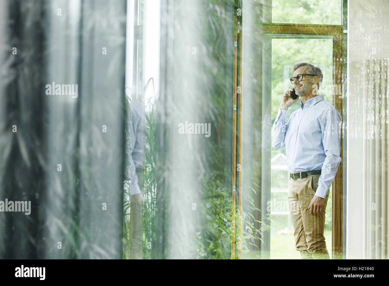 Man on the phone in his house looking through window Stock Photo - Alamy