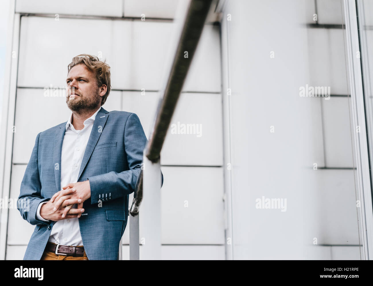 Businessman leaning on railing Stock Photo - Alamy