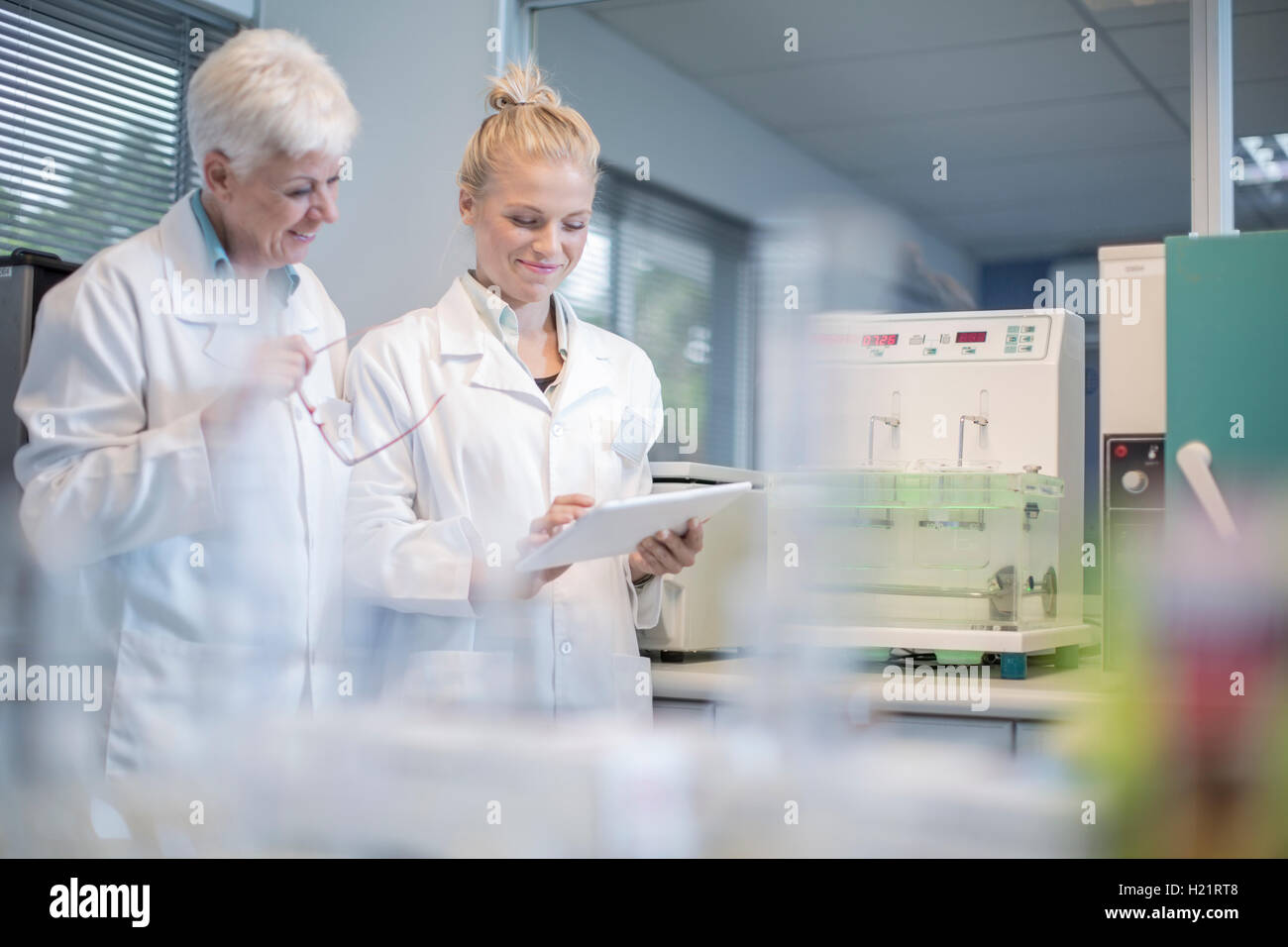 Two smiling women in lab looking at tablet together Stock Photo - Alamy